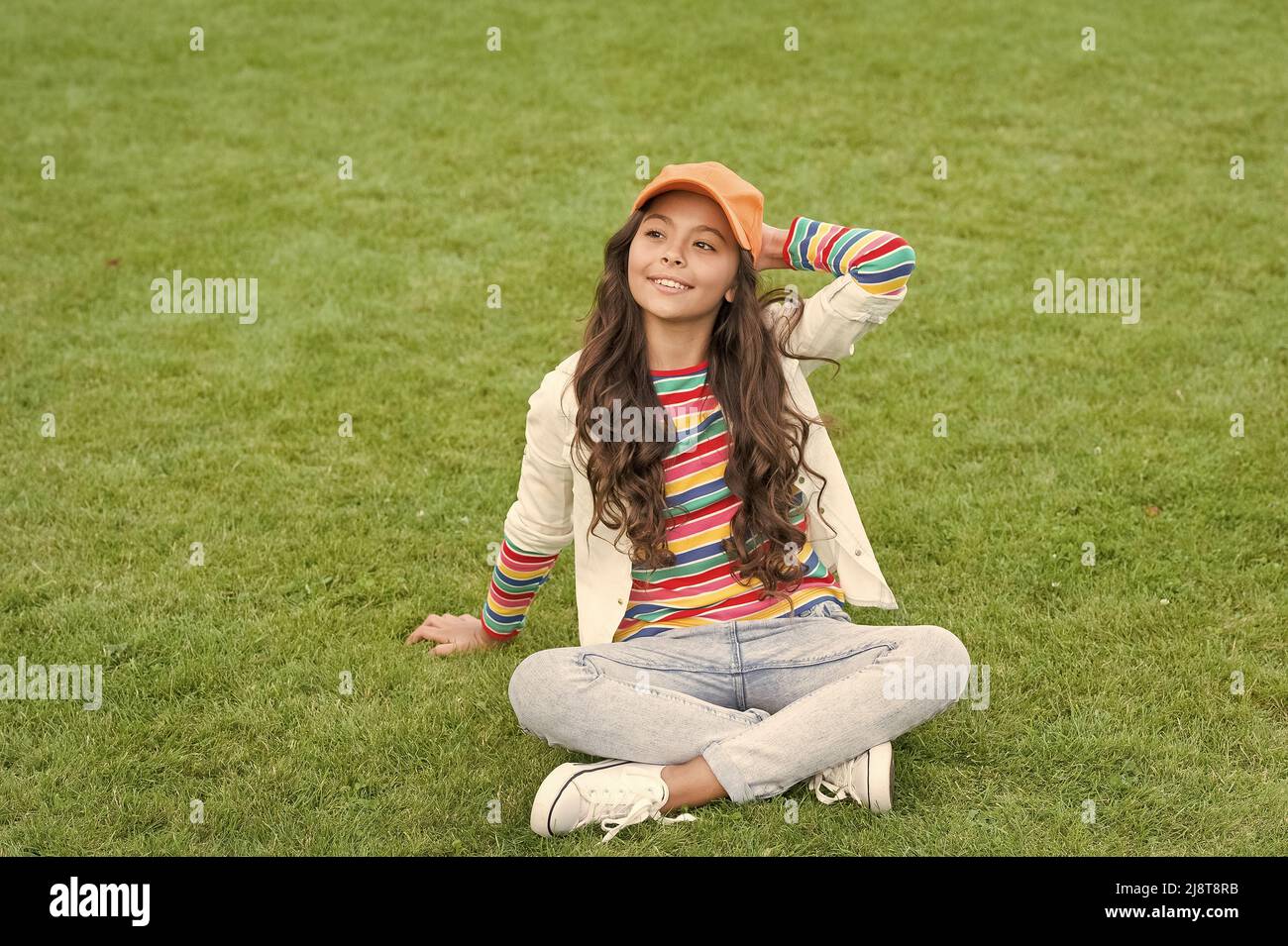 Happy school age girl kid smile sitting on green grass, child Stock ...