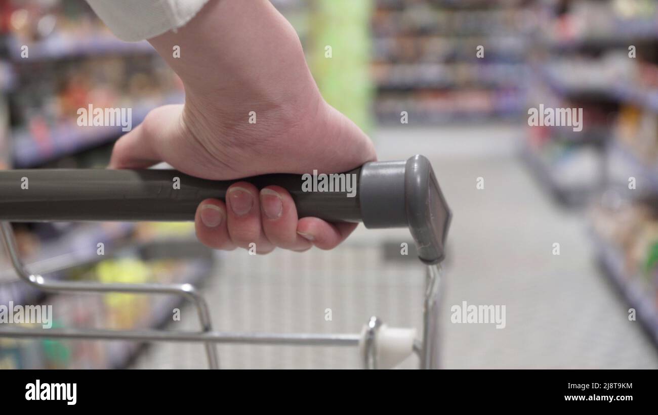 A woman's hand on the handle of a grocery cart at the supermarket Stock ...