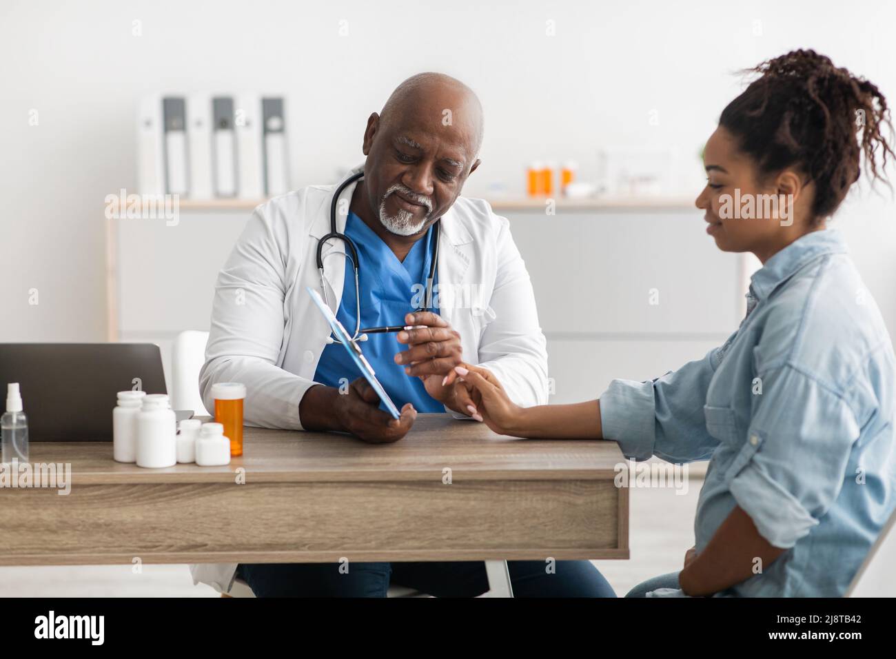 Experienced black doctor explaining treatment plan to female patient ...