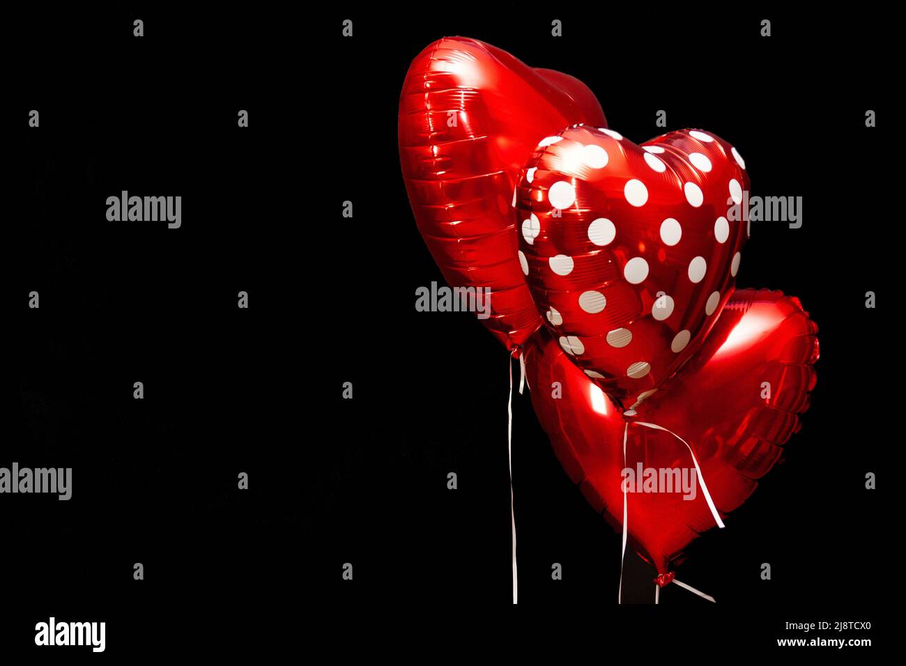 Inflatable big bright red balloons in the shape of a heart on a black ...