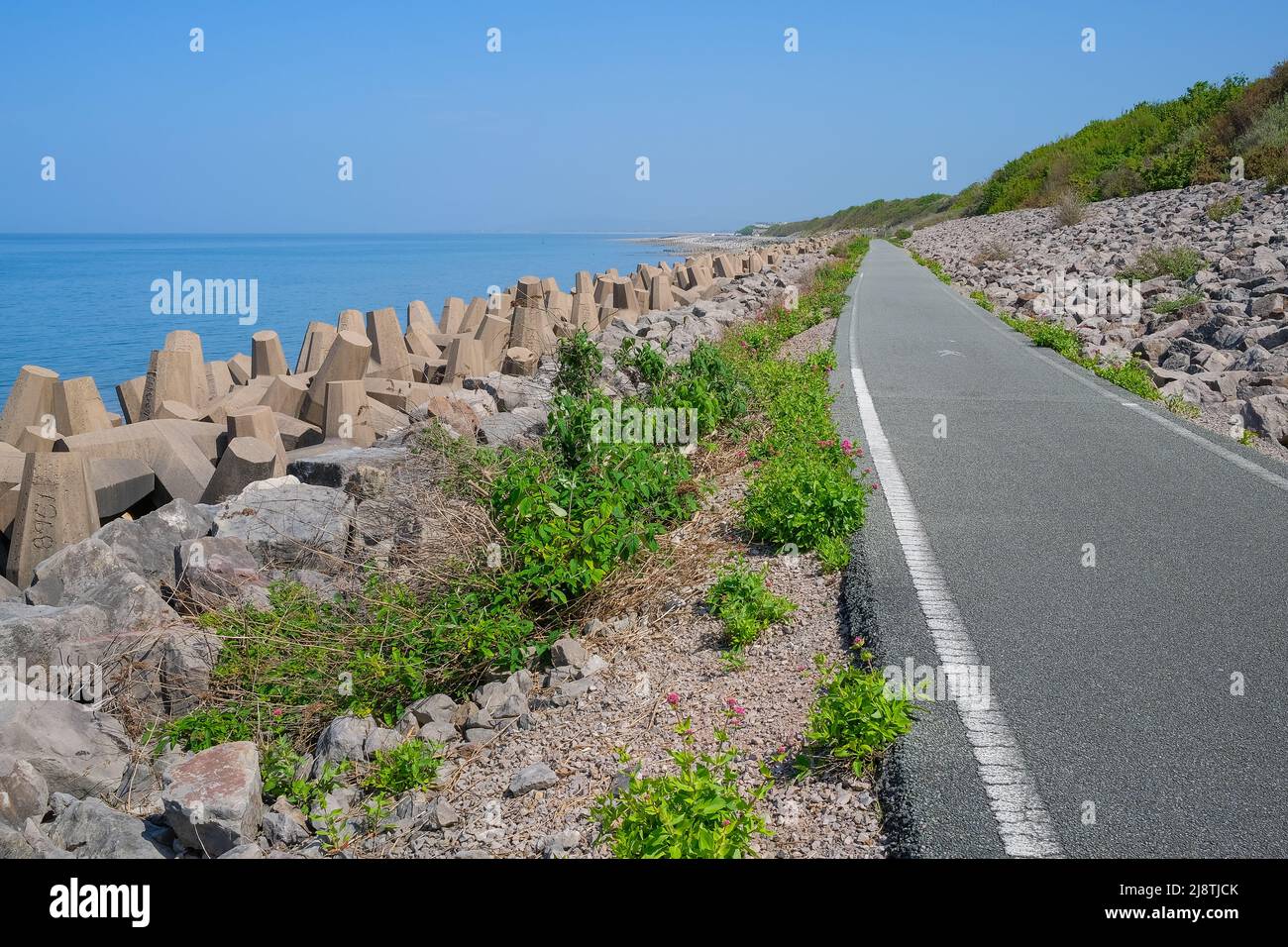 North Wales coastline cycle path next to sea defense concrete groynes ...