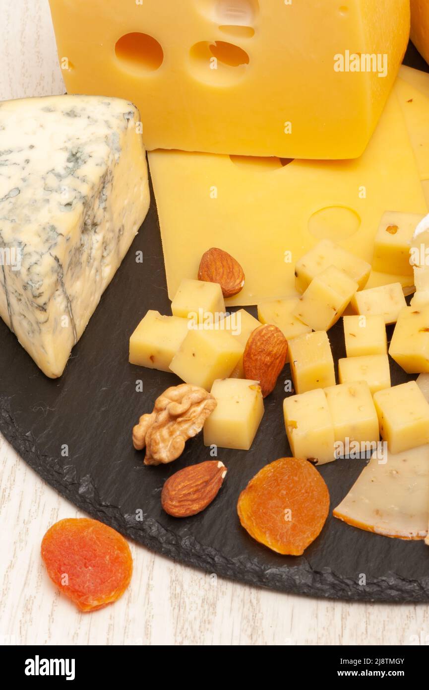 Different types of cheese on a graphite board with nuts and dried ...