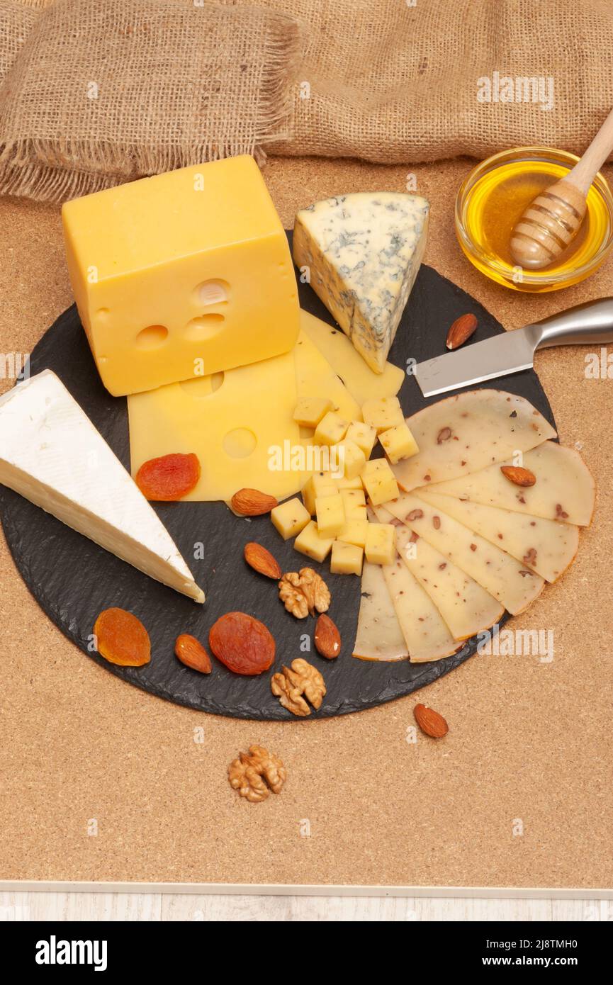 Different types of cheese on a graphite board with nuts and dried ...