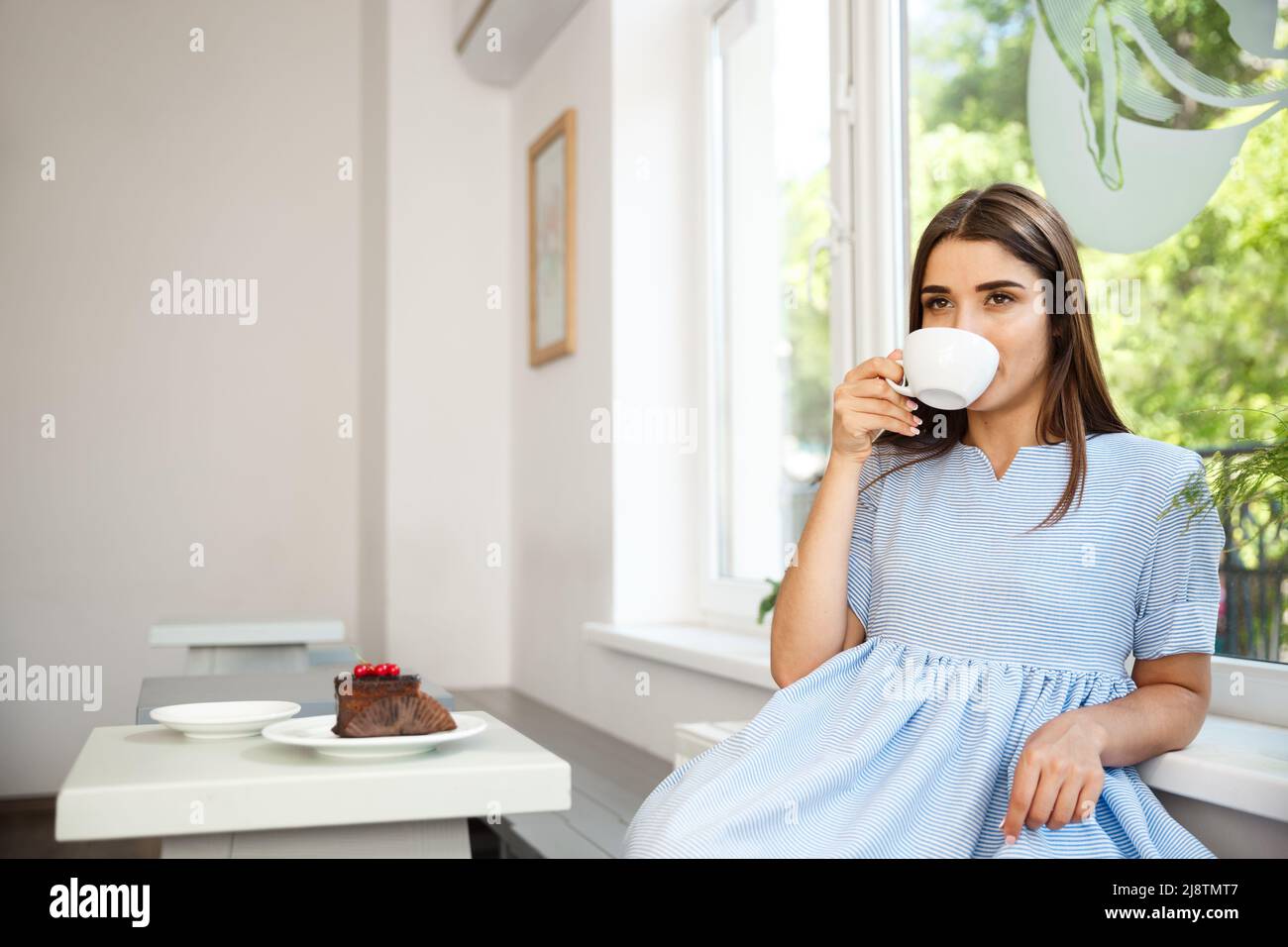 Young beautiful Caucasian lady enjoy drinking and having dessert in ...