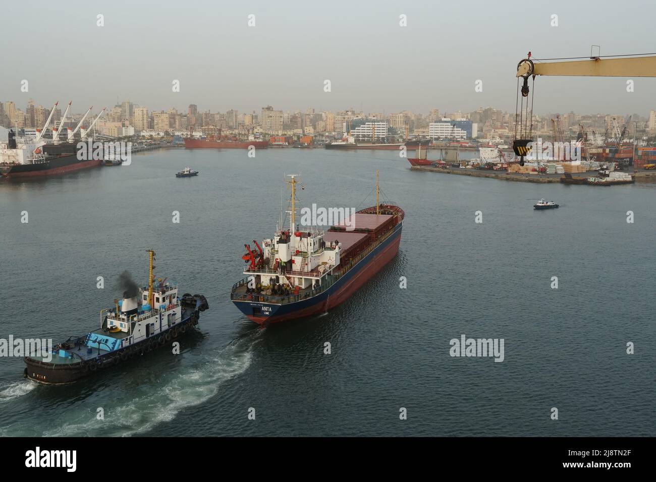 Small bulk carrier assisted by tugboat during approaching berth in port ...