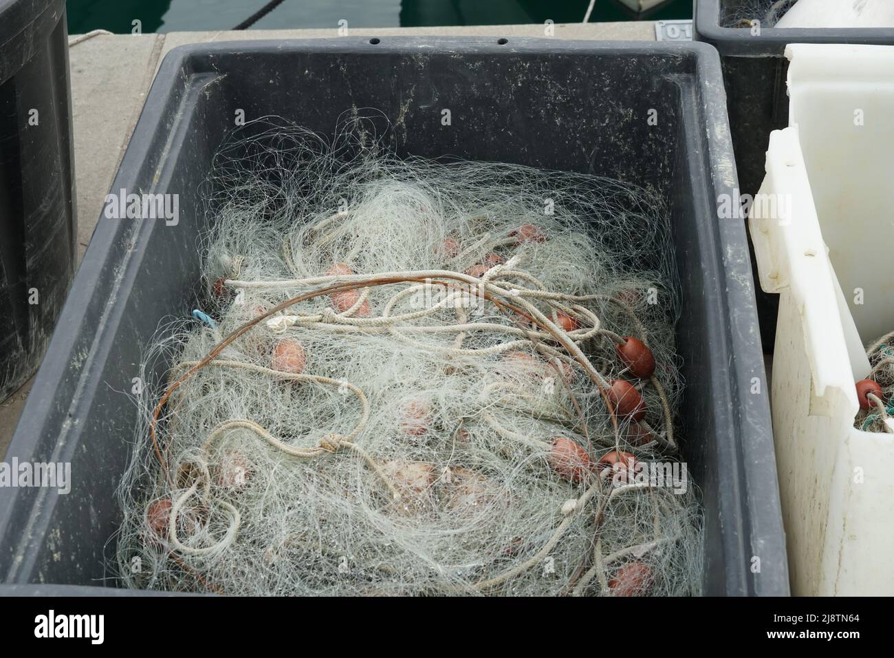 Fishing net with white ropes and red-brown floats stored in black ...