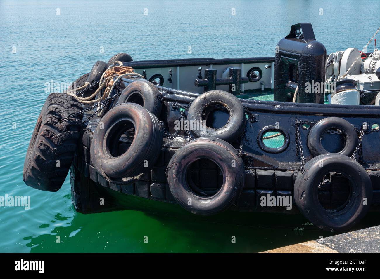 The tugboat stands at the pier in the seaport on a sunny summer day ...