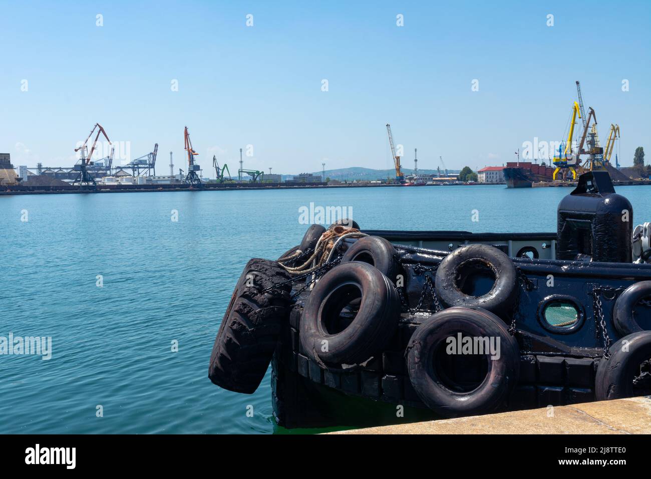 The tugboat stands at the pier in the seaport on a sunny summer day ...