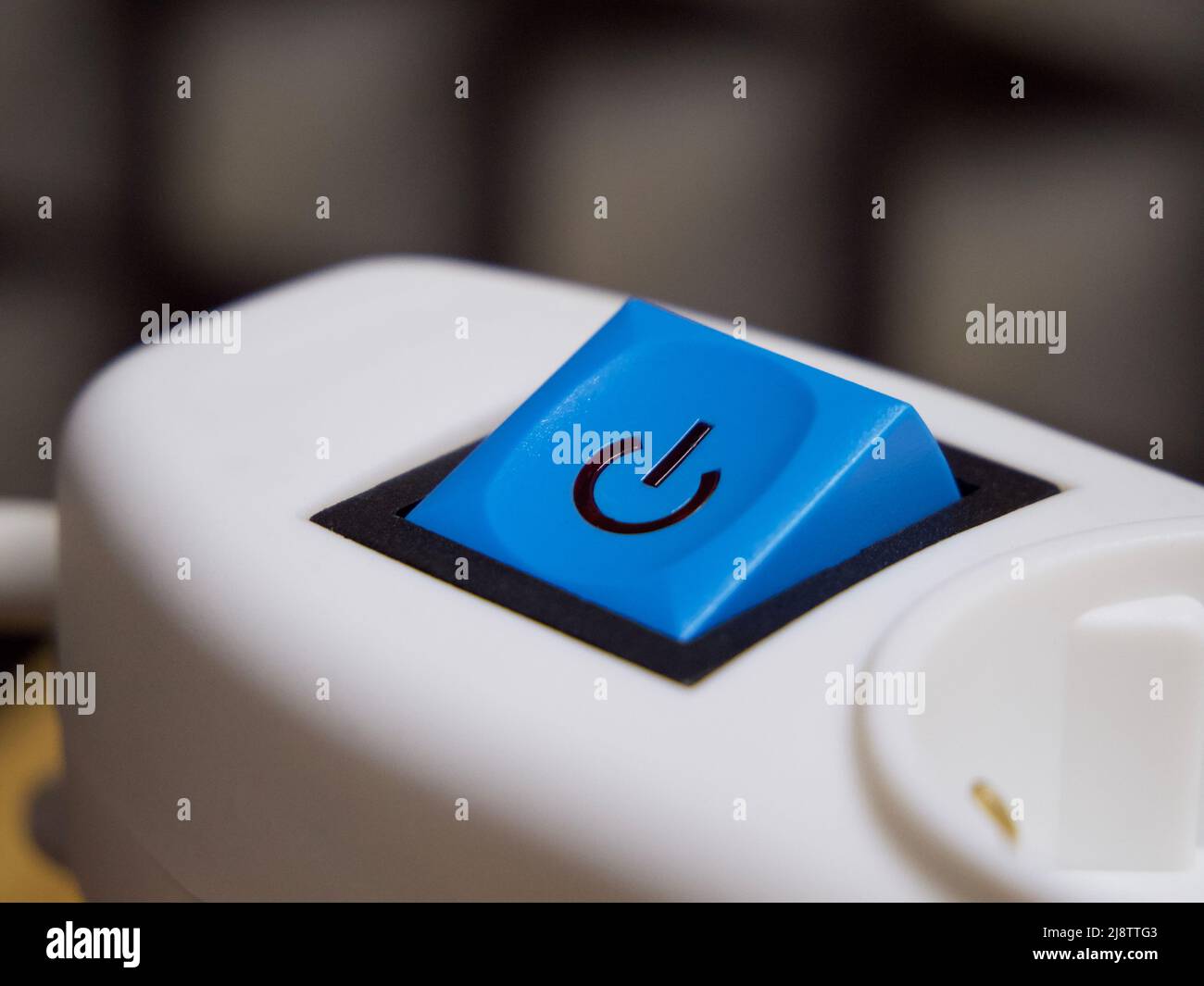 Blue power button on white extension cable. Power button, close-up shot ...