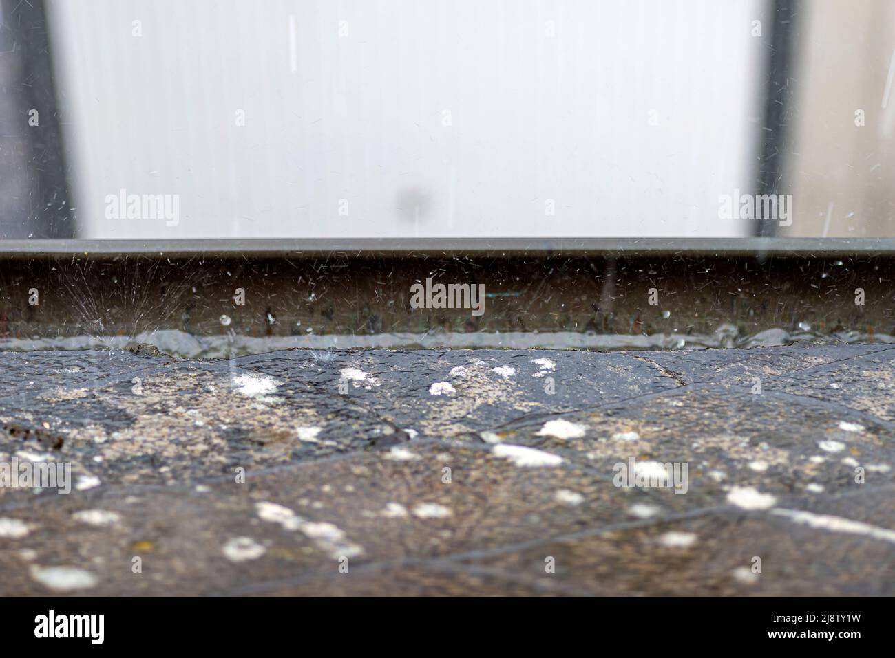 Heavy rain falling on the roof overflowing the gutter with water in ...