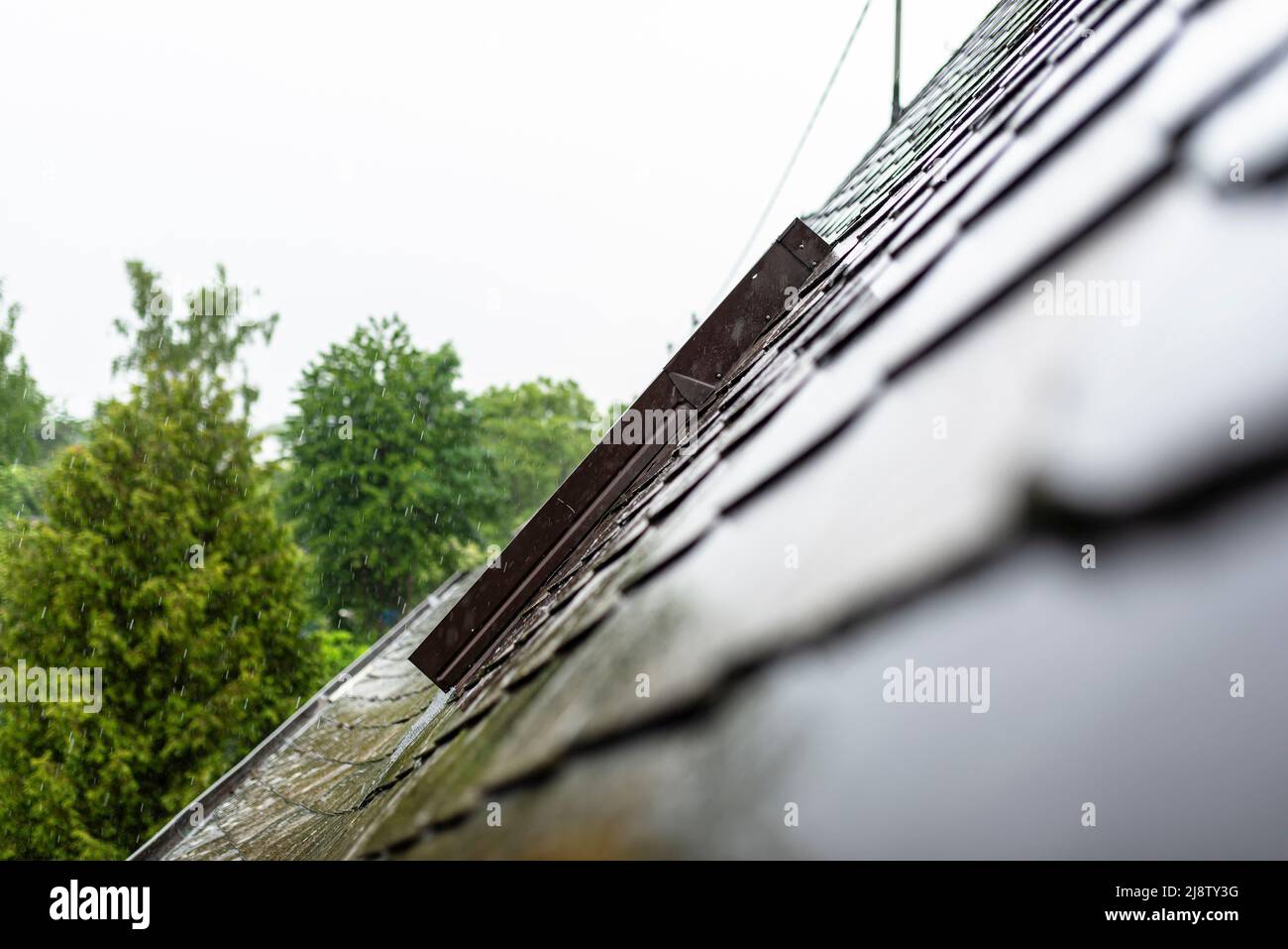 Heavy rain falling on the roof overflowing the gutter with water in ...