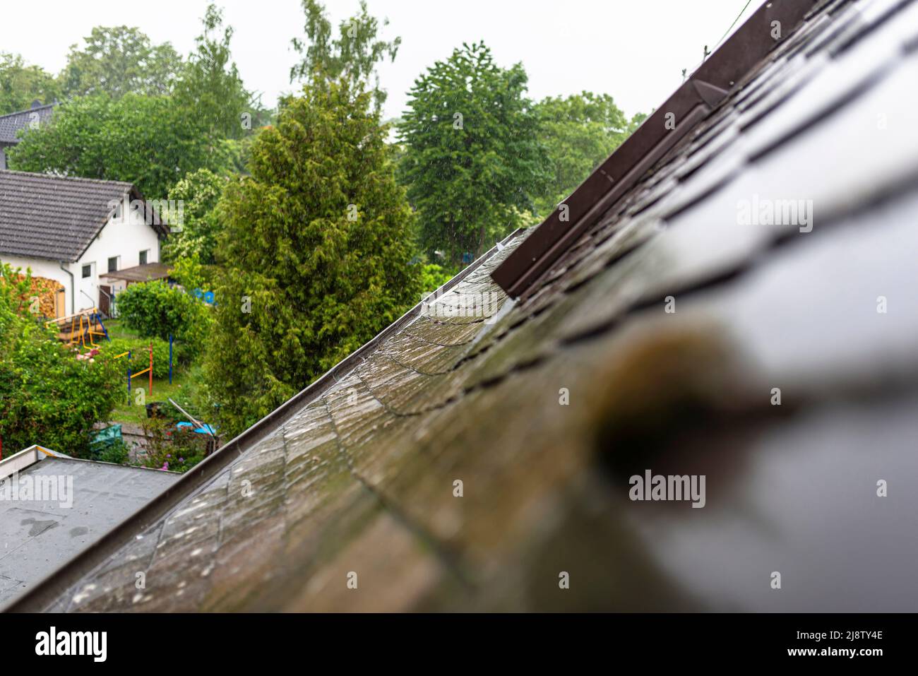 Heavy rain falling on the roof overflowing the gutter with water in ...