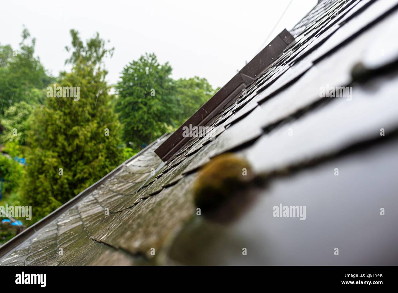 Heavy rain falling on the roof overflowing the gutter with water in ...