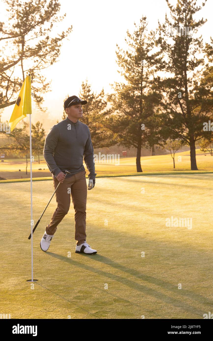 Full length of caucasian young man with golf club walking at golf ...