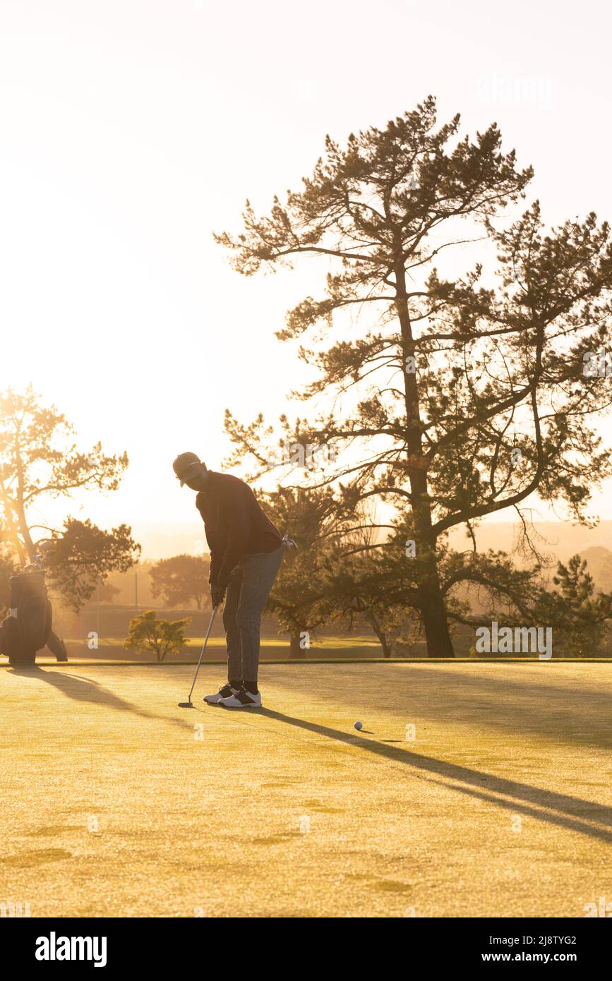 African american young man playing golf on grassy land against clear ...