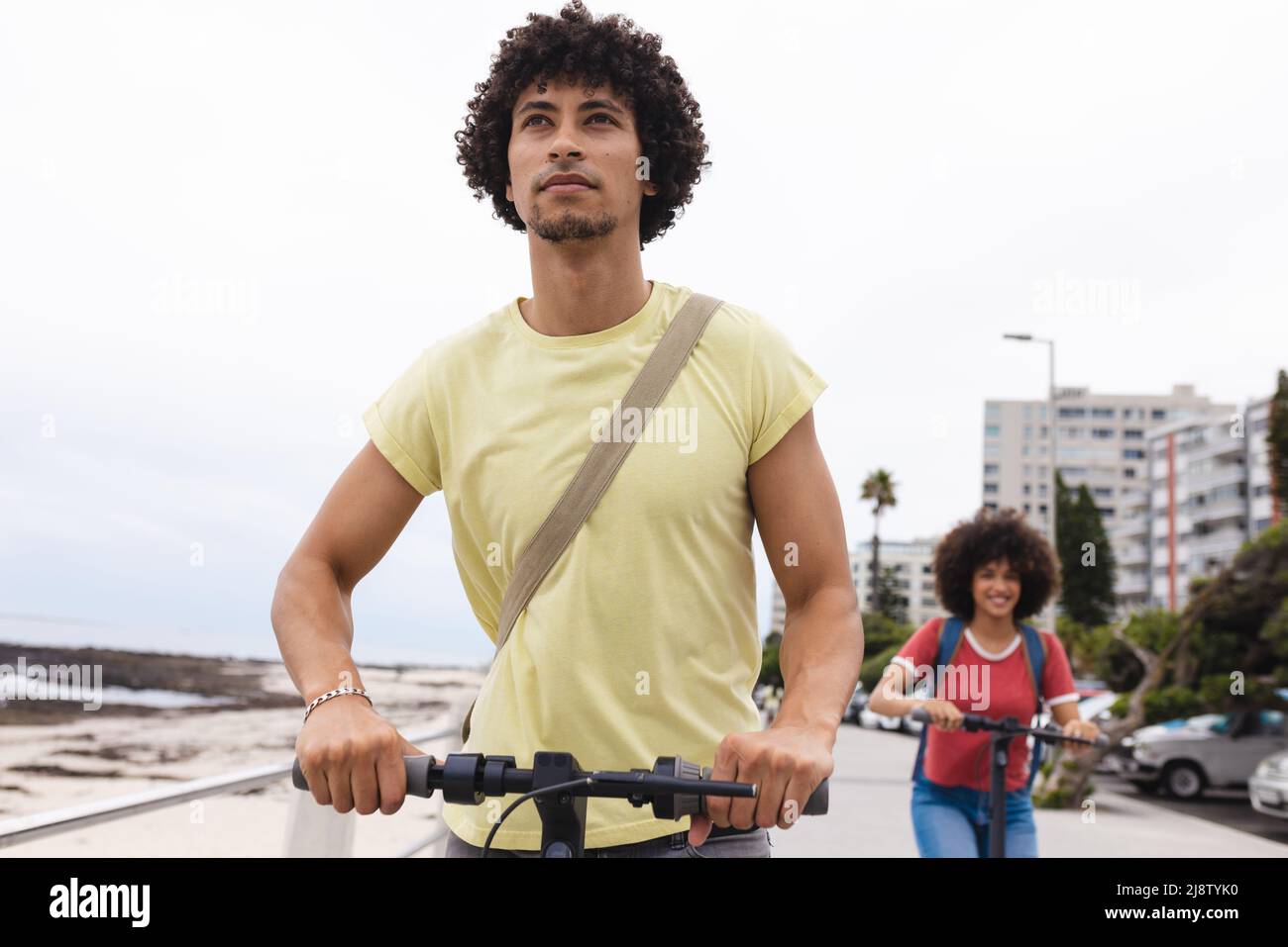 Young afro african american couple riding push scooters in city, copy ...