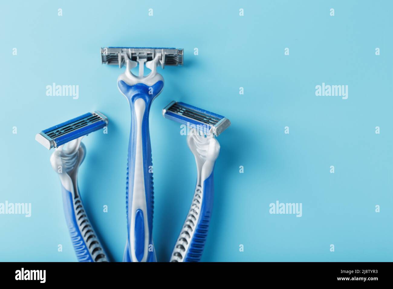Three shaving machines on a blue background with free space, top view ...