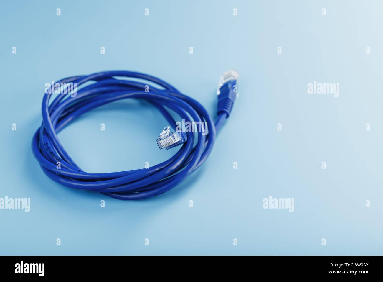 A coil of RJ45 Cat.6 Ethernet Network Internet Cable isolated on a blue ...