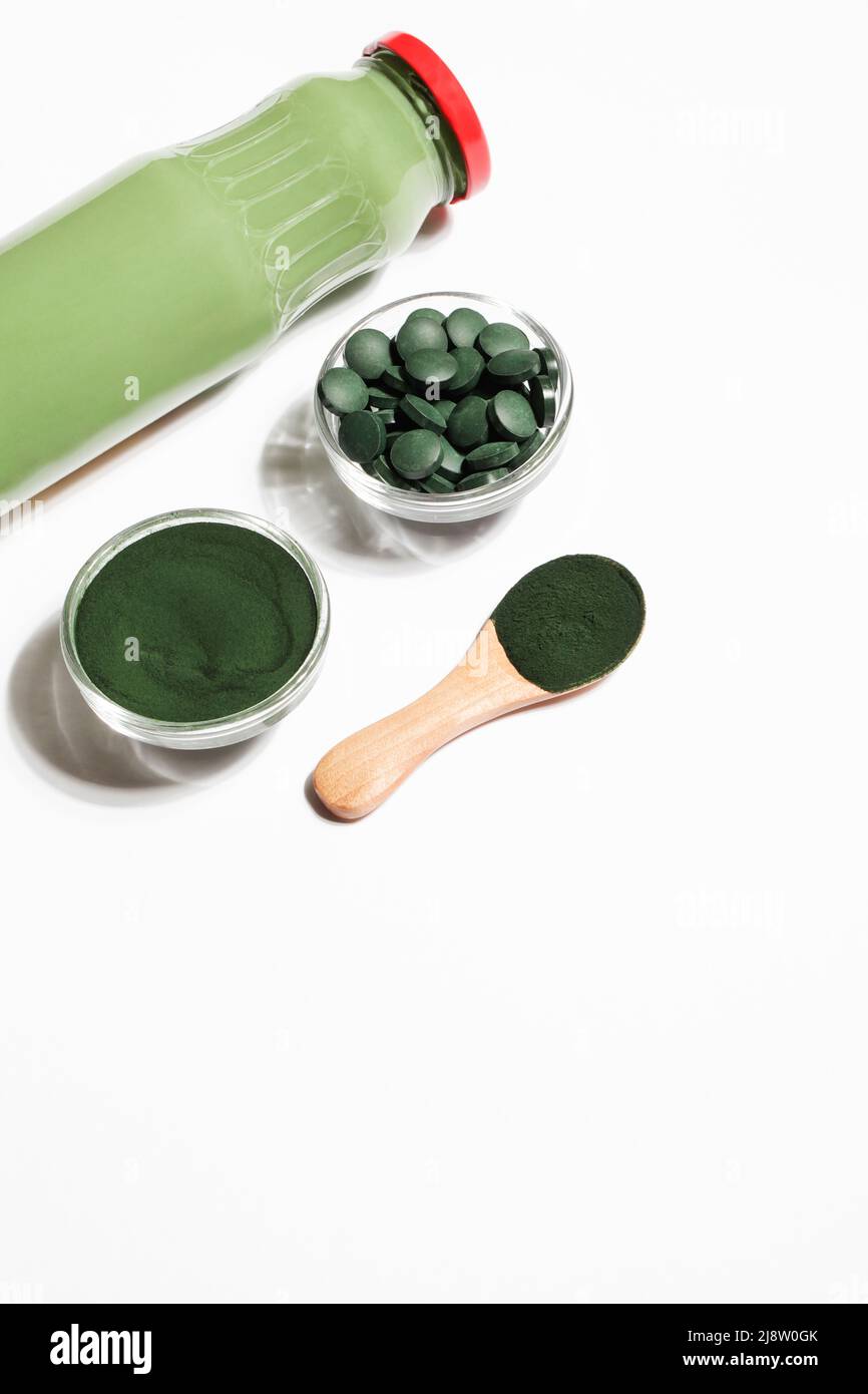 green smoothie in bottle and spirulina algae powder and pills in glass ...