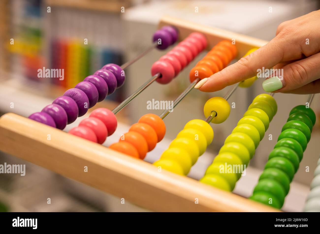 Closeup female hand calculating with balls on wooden rainbow abacus for ...