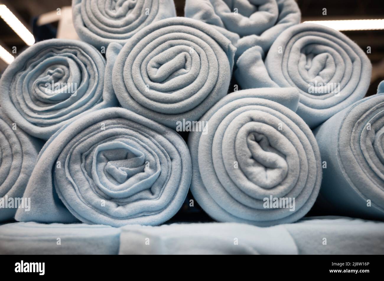 A stack of knitted white plaid folded into a roll. Several handmade ...