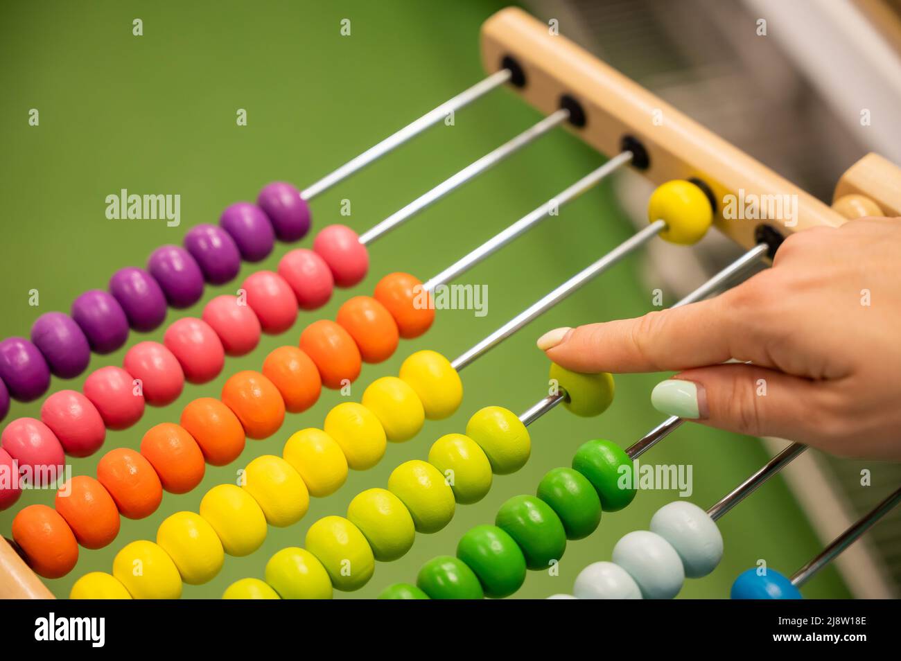 Closeup female hand calculating with balls on wooden rainbow abacus for ...