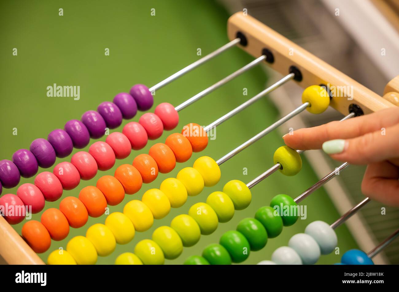 Closeup female hand calculating with balls on wooden rainbow abacus for ...