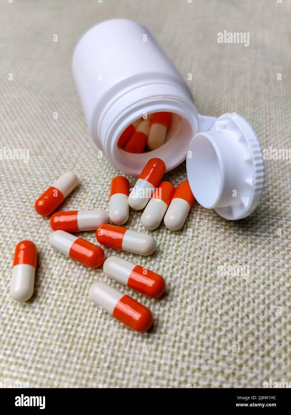 Two-color medicinal capsules in gelatin shell spilled out of plastic ...