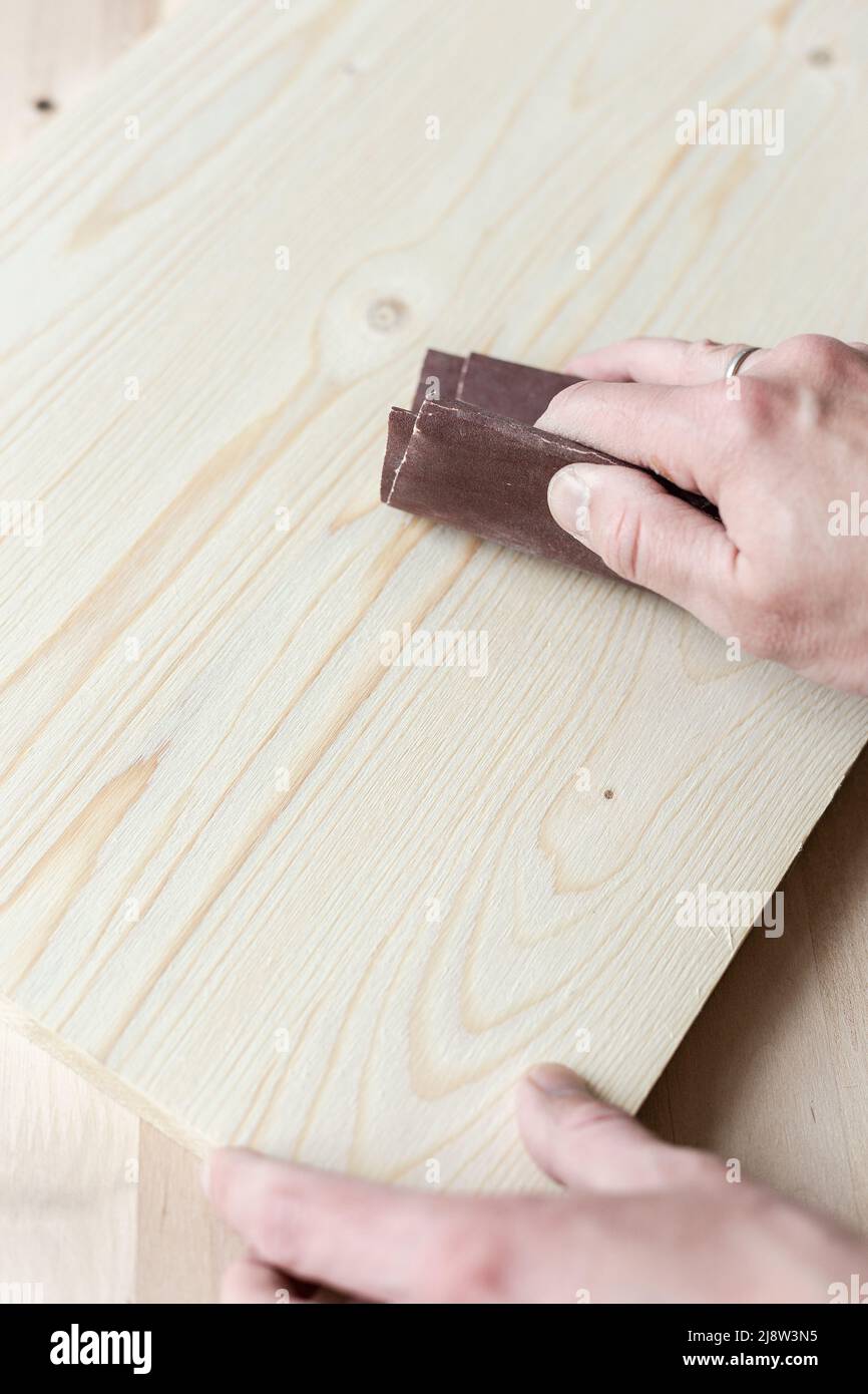 Sanding boards by hand. Sanding with abrasive paper Stock Photo - Alamy