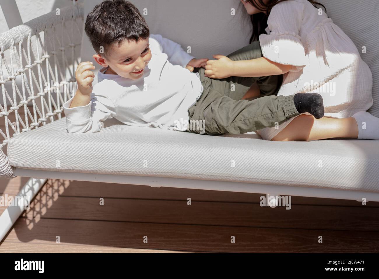 Two happy cute little siblings having fun on a swing bench together on ...