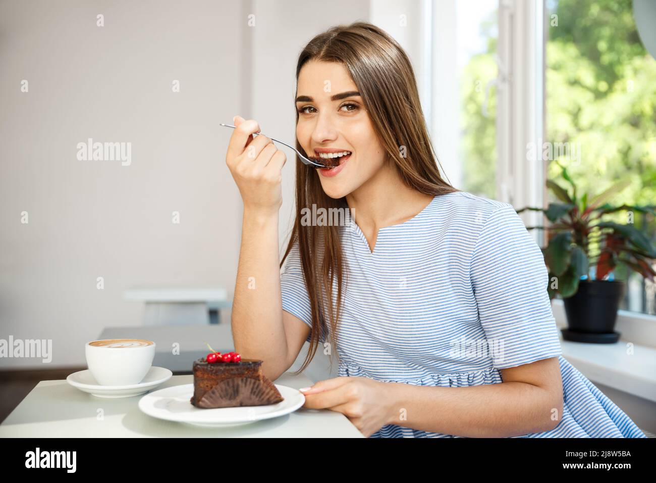 Young attractive Caucasian lady enjoy eating chocolate cake with hot ...