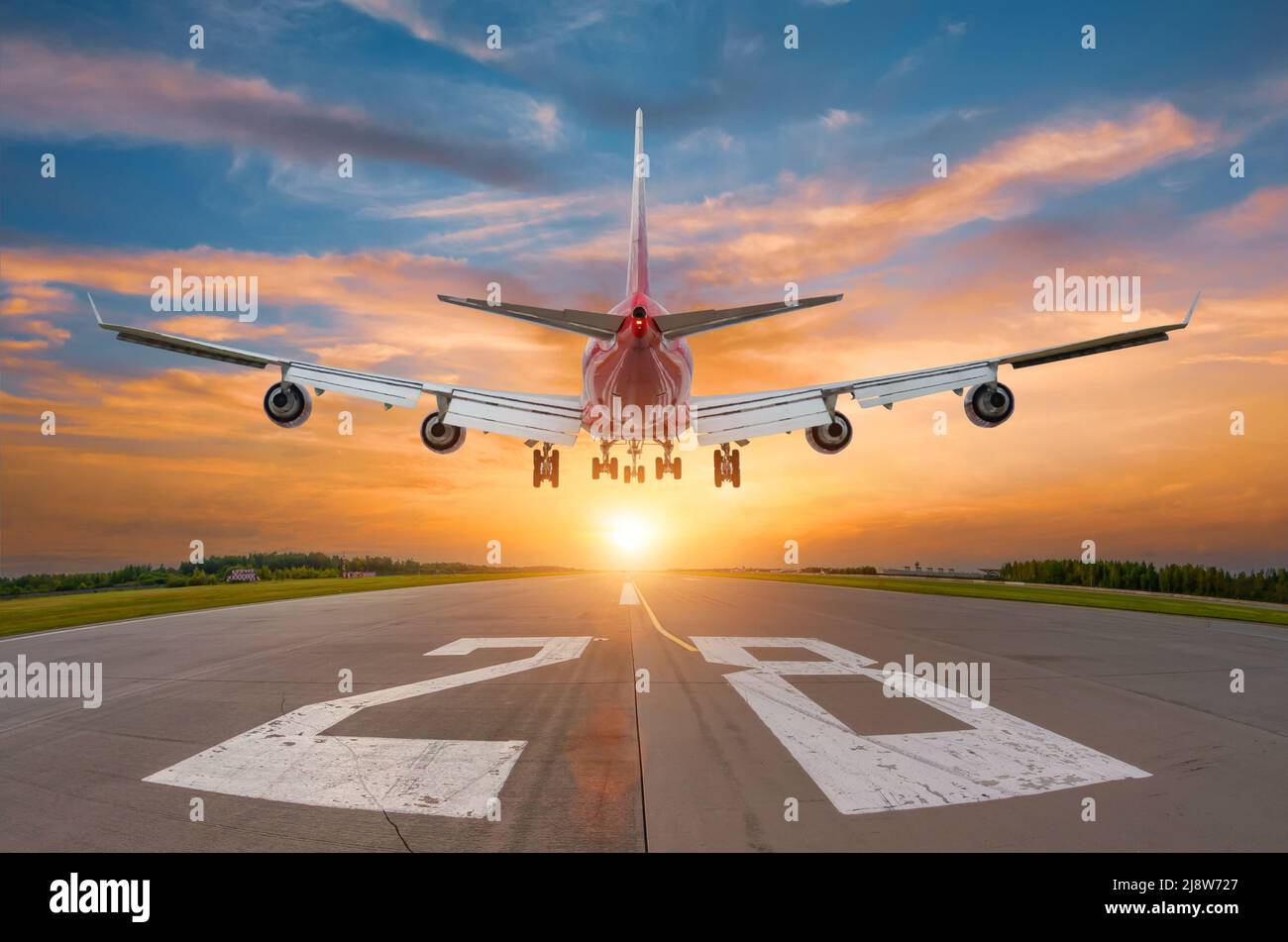 The plane lands on the runway during dawn, rear view from the end of ...