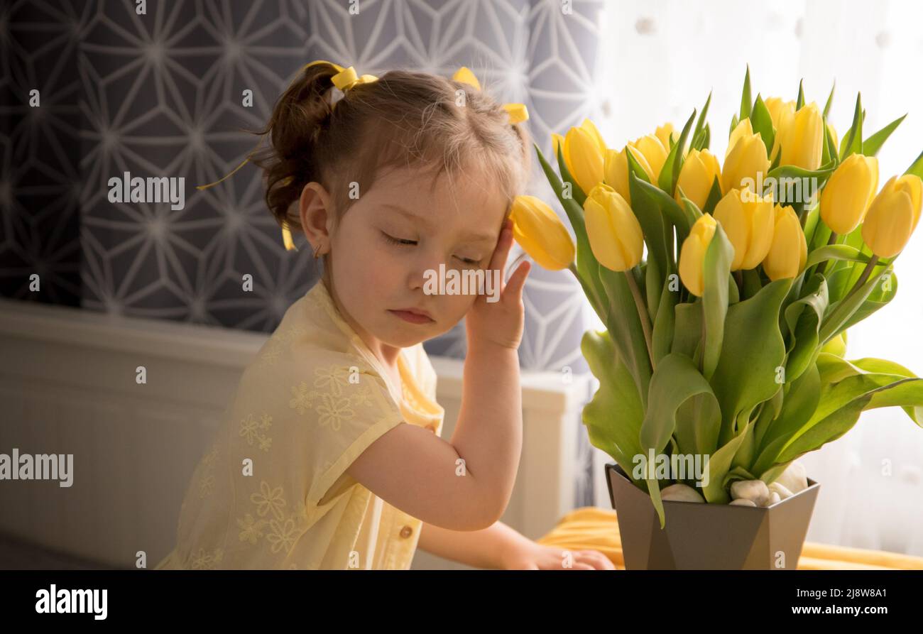 A sad girl with a bouquet of yellow tulips looks to the side. The ...