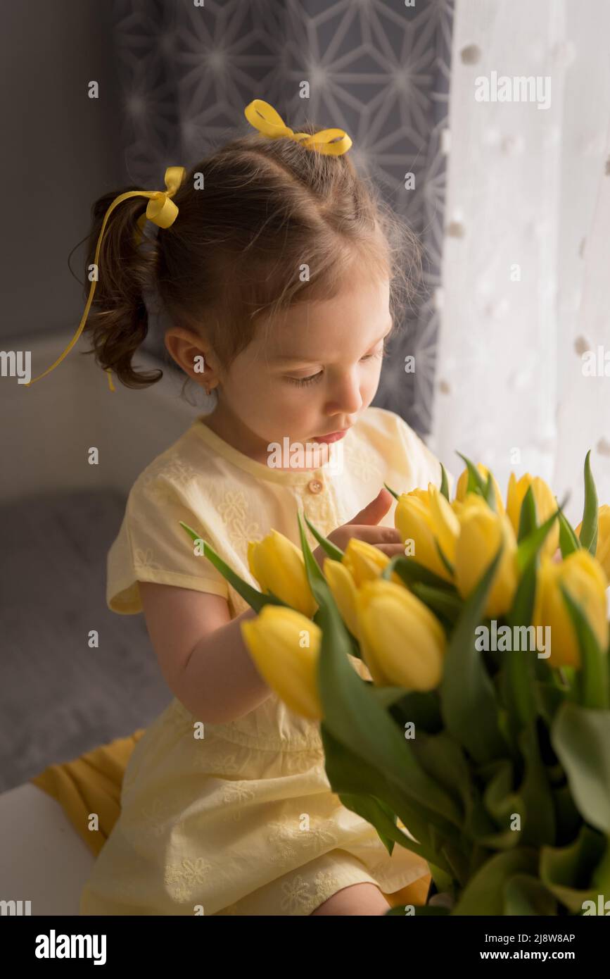 A sad girl with a bouquet of yellow tulips looks to the side. The ...