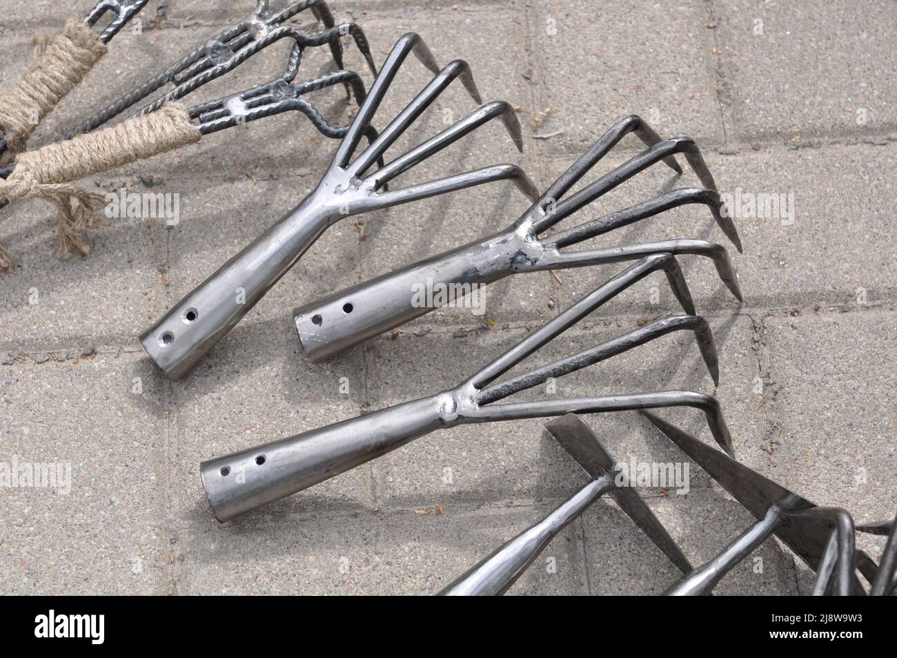 Small iron rake, gardening tool. Set of gardening hoes Stock Photo - Alamy