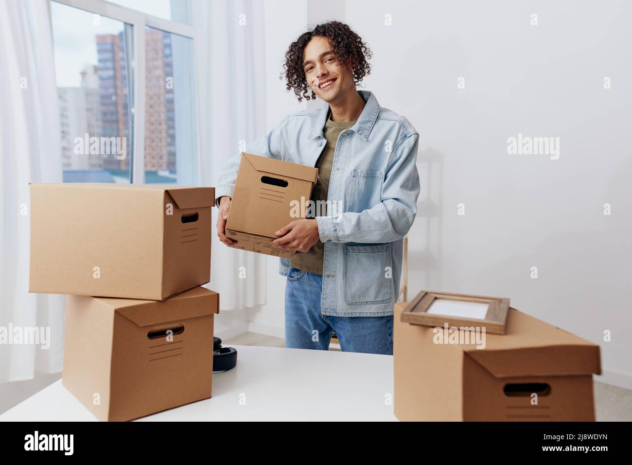 guy with curly hair unpacking with box in hand sorting things out Stock ...