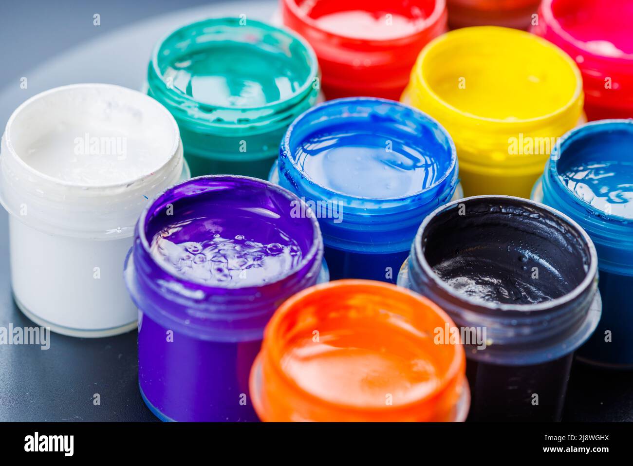 full-frame close-up background of opened small gouache paint jars on ...