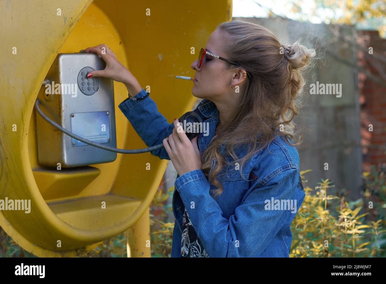 a girl in a blue denim jacket, sunglasses and with a cigarette in a ...