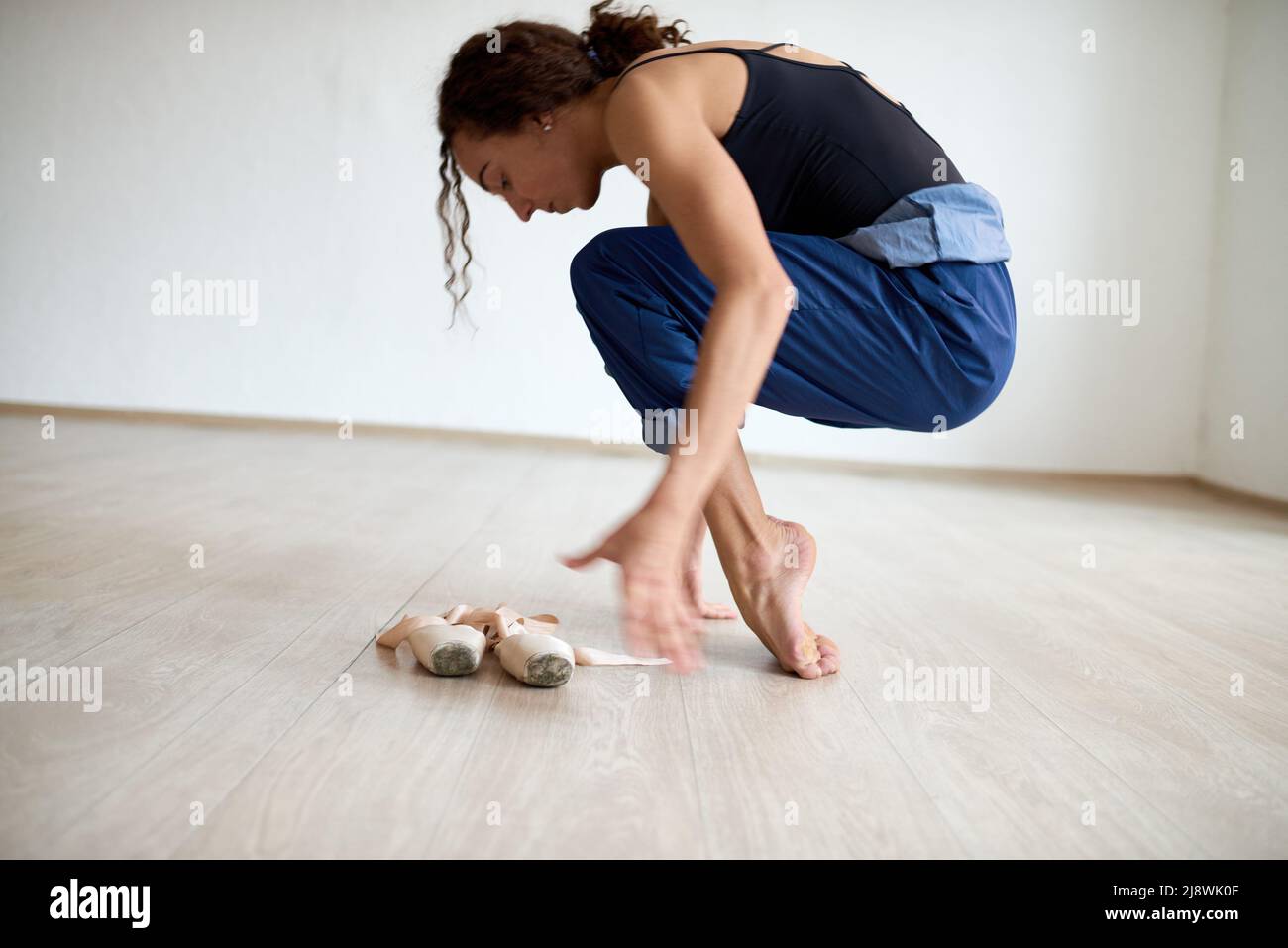 Young female dancer sitting on tips of toes during rehearsal in dancing ...