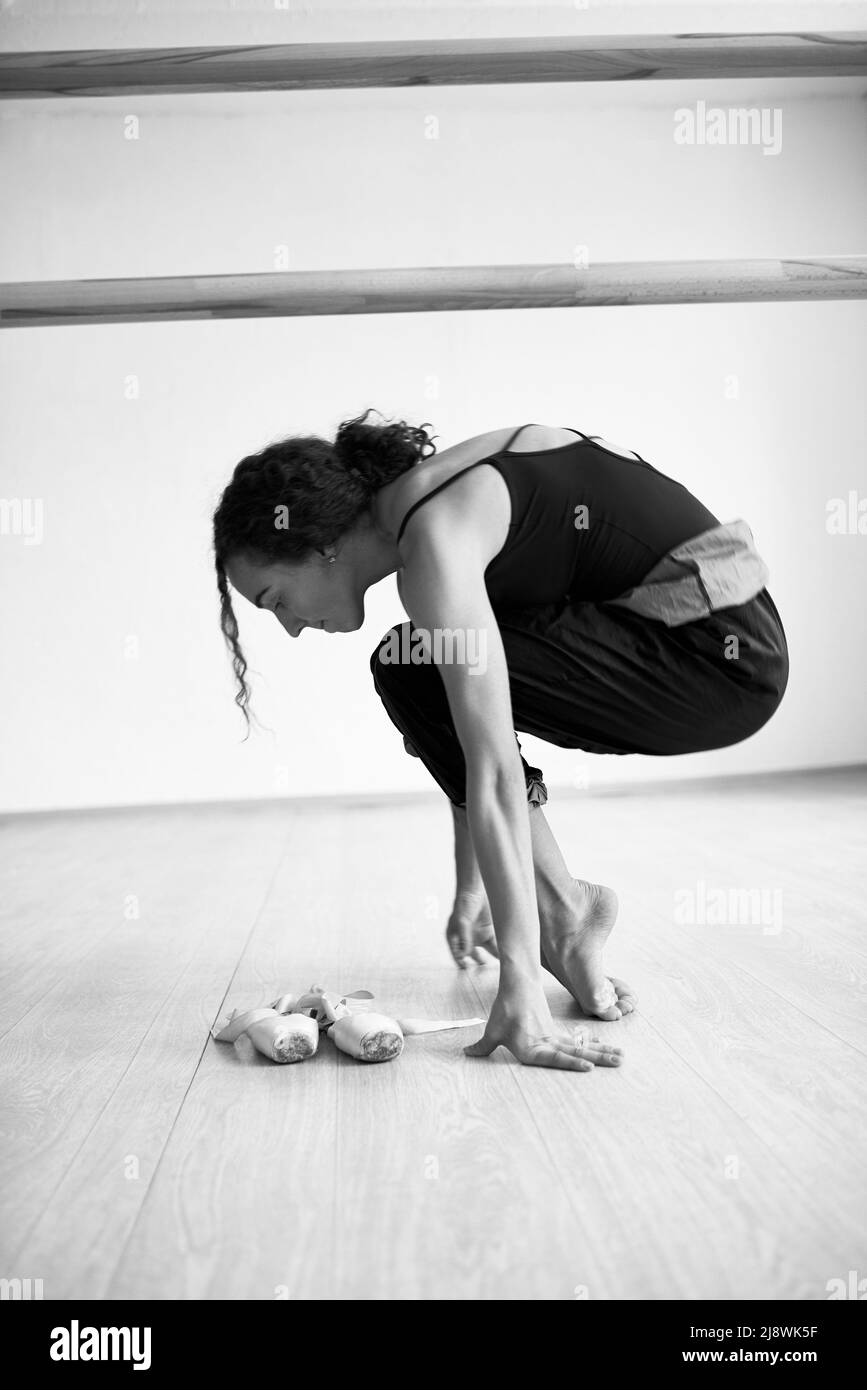 Black and white shot of young woman trying to get up on tips of toes in ...