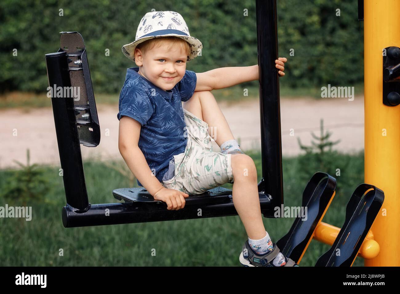 Boy child doing sports exercises on the outdoor sports ground. The ...