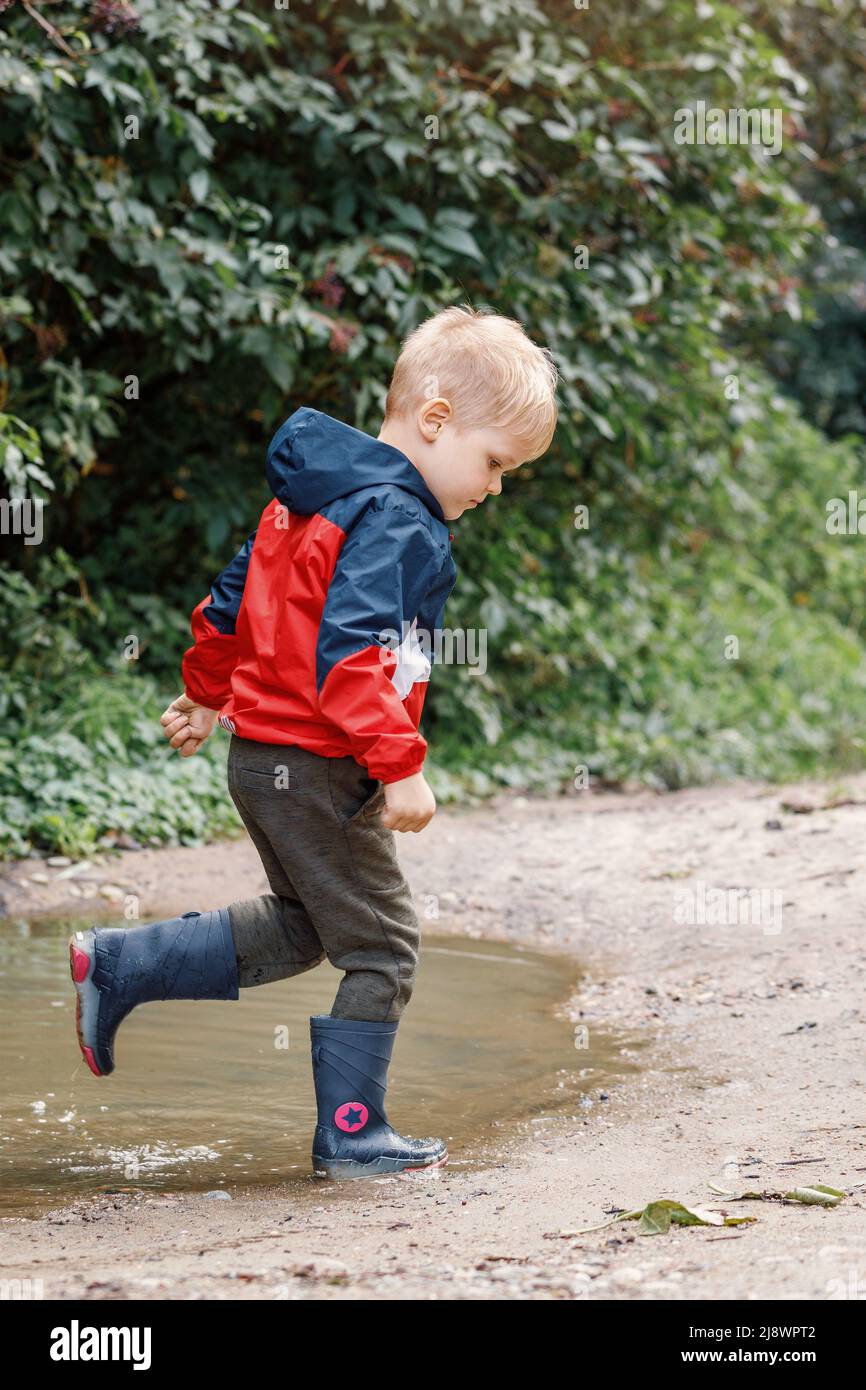 Little boy splashing in a mud puddle, jumping into a puddle Stock Photo ...