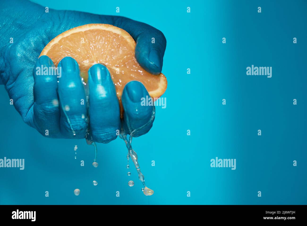 Close-up shot of fresh juice dripping from ripe half of orange while ...