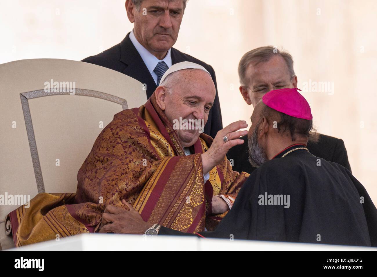 Pope Francis is being helped to wear a garment he received from a ...