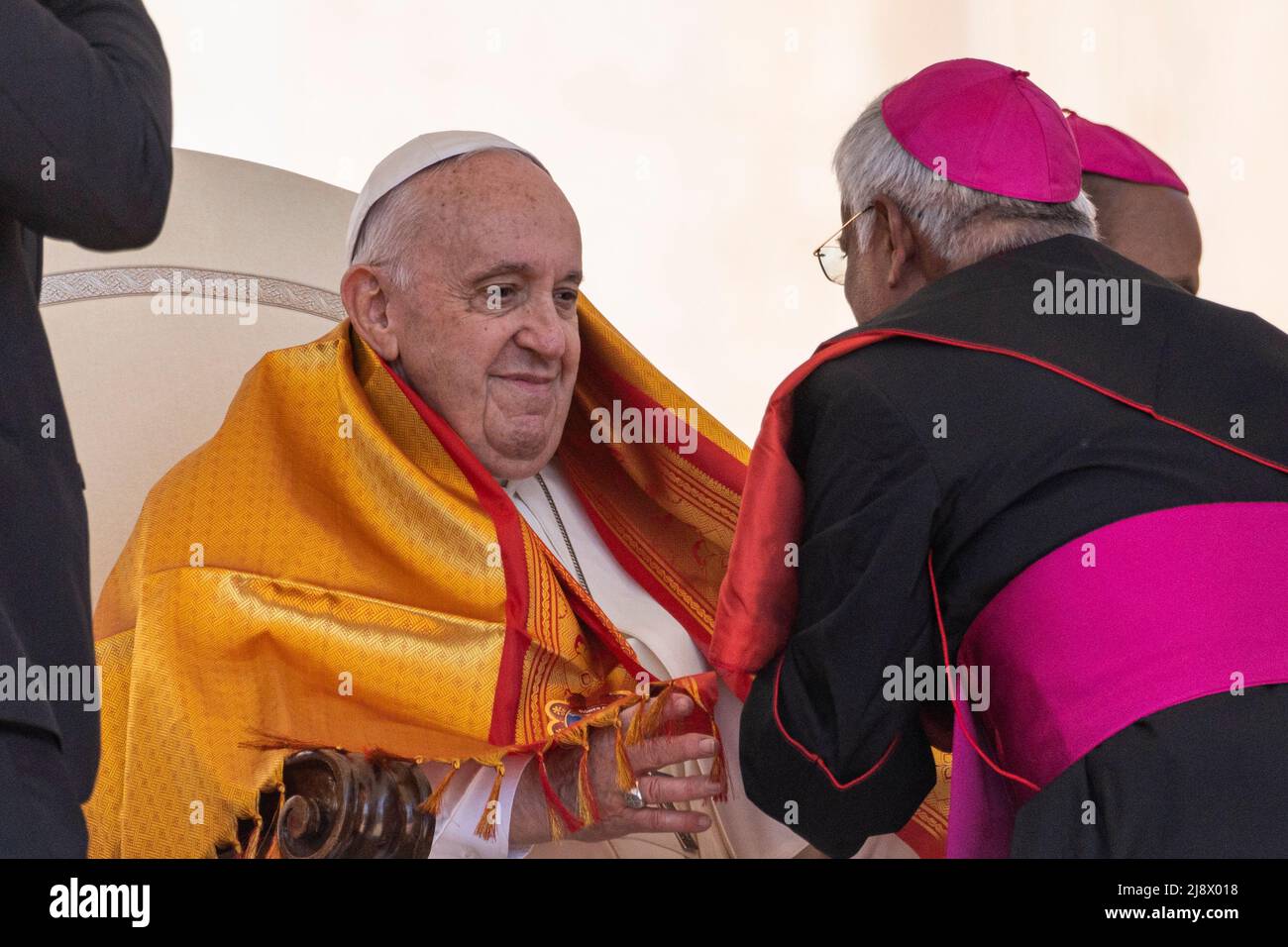 Pope Francis is being helped to wear a garment he received from a ...