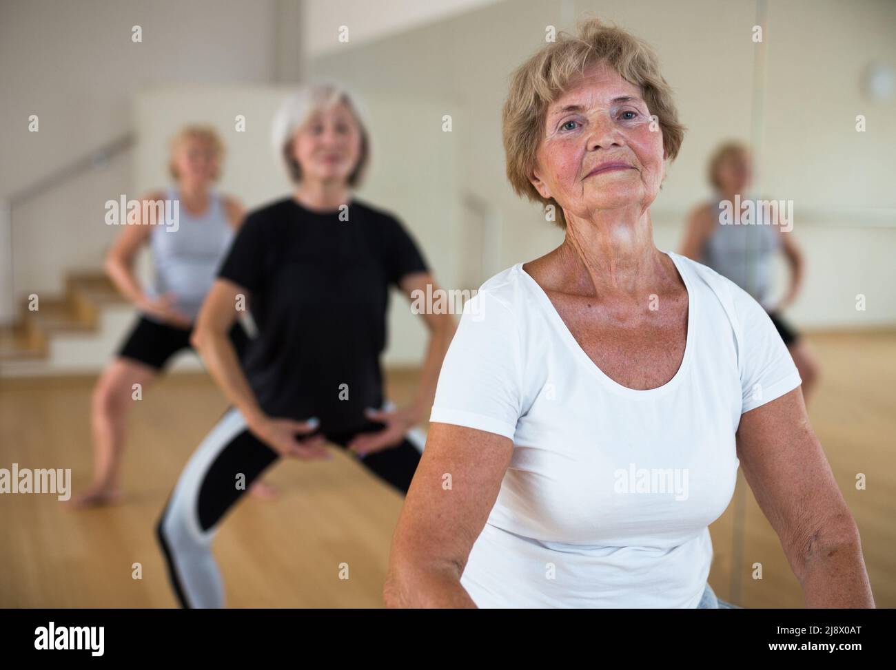 Mature women perform a plie squat while in the position of a ballet ...