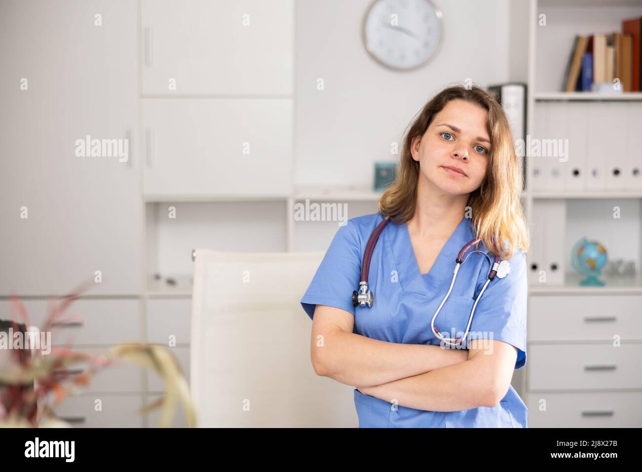Portrait of female doctor who is working and posing on her workplace in ...
