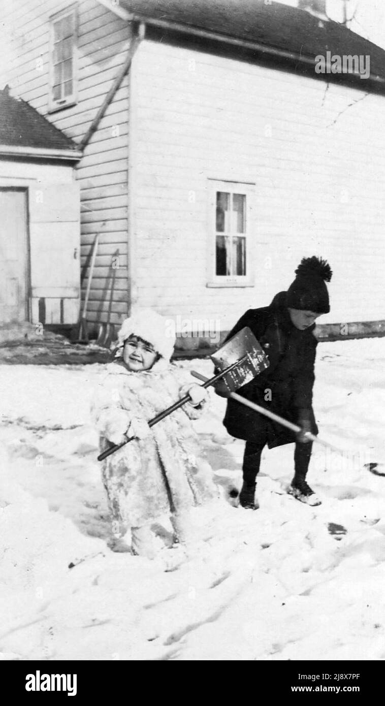 Two young children shovelling snow ca. 1930 Stock Photo - Alamy