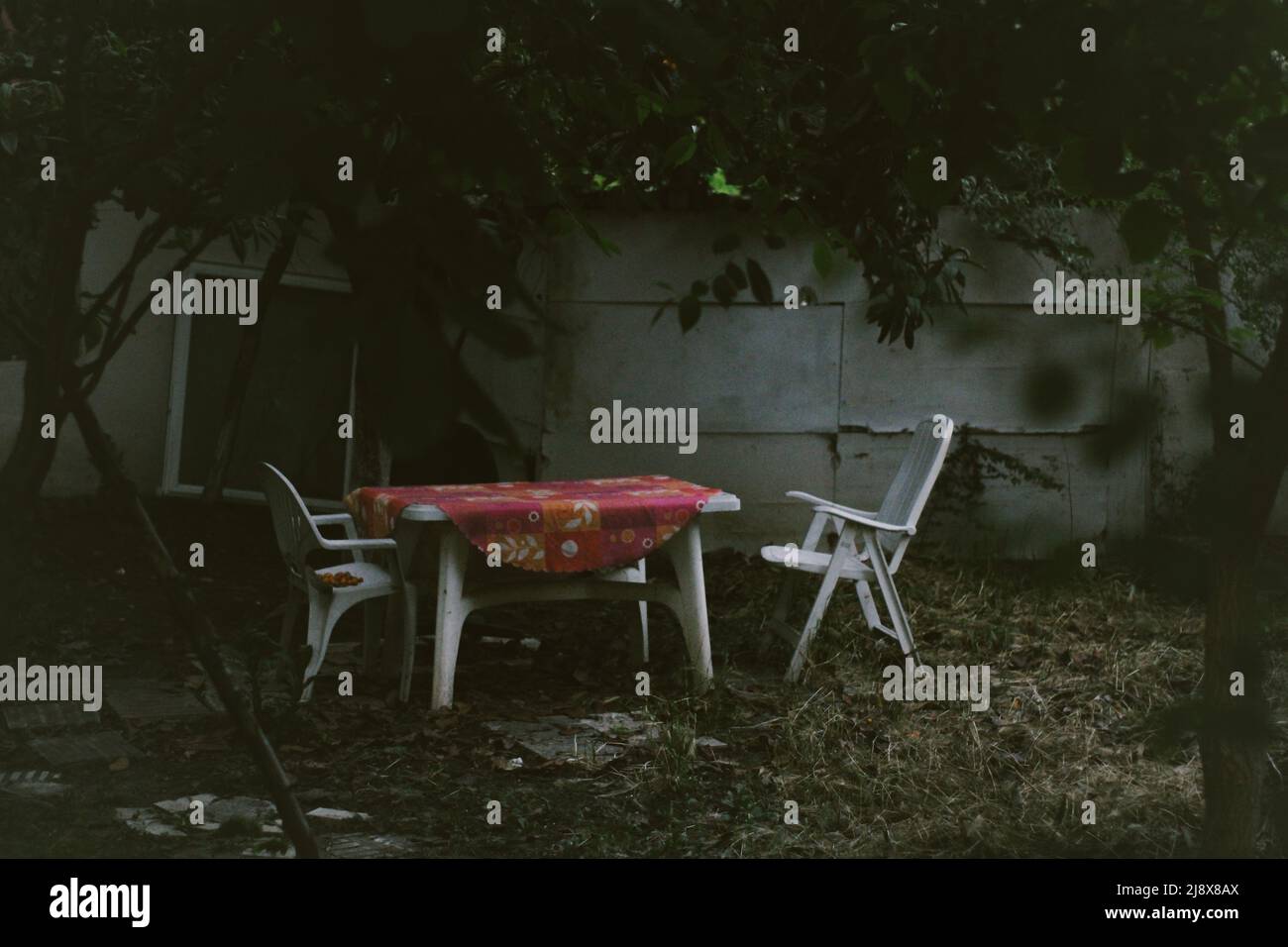 Tables and chairs in the creepy garden Stock Photo - Alamy