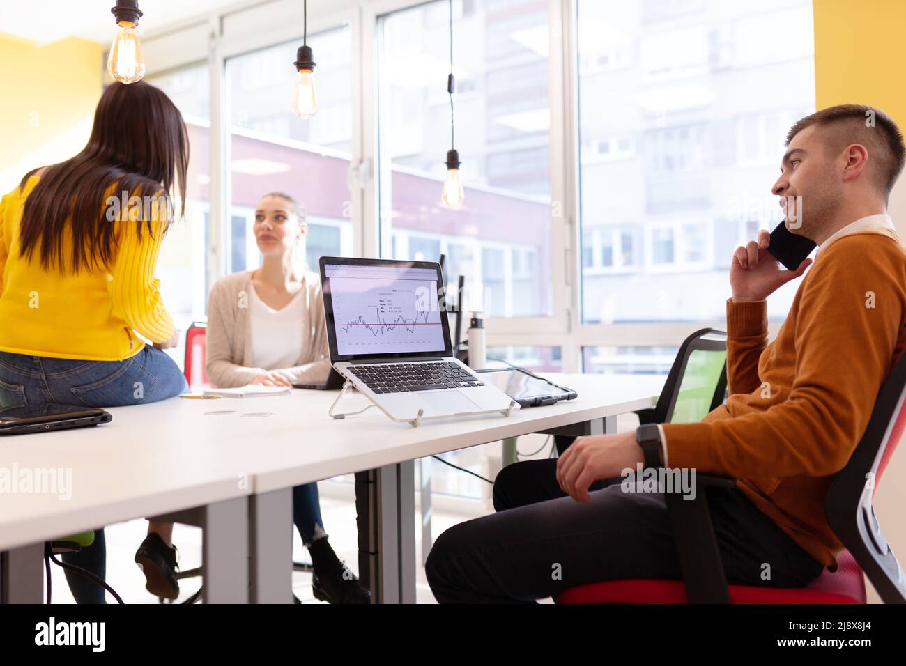 Creative team of young individuals working on desktop and laptop ...